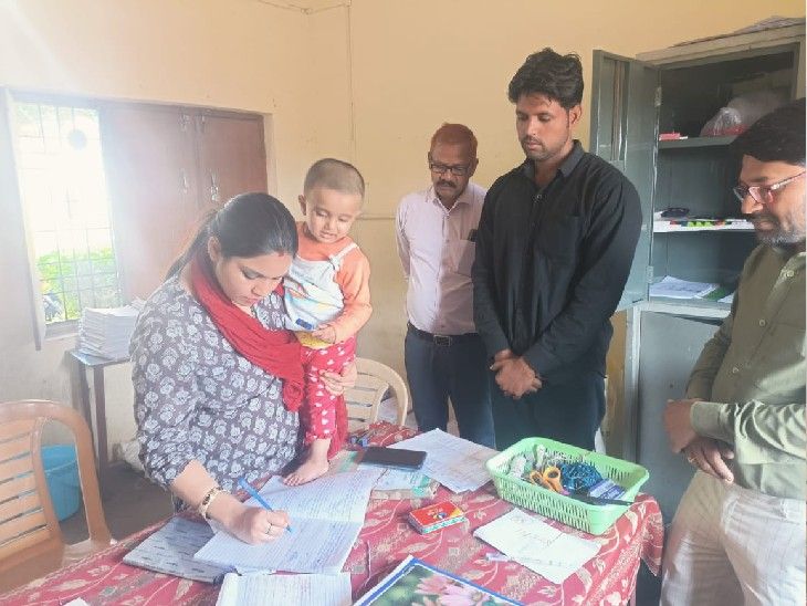 Naib Tehsildar doing duty with one year old daughter in her lap
