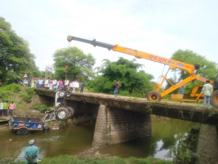 A tractor-trolley filled with bars fell into the river below the bridge ...