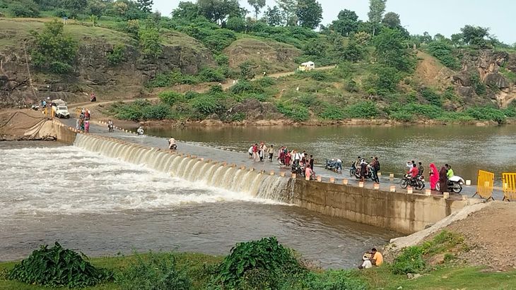 Dam gates opened, water flowing over culvert, people passing out ...