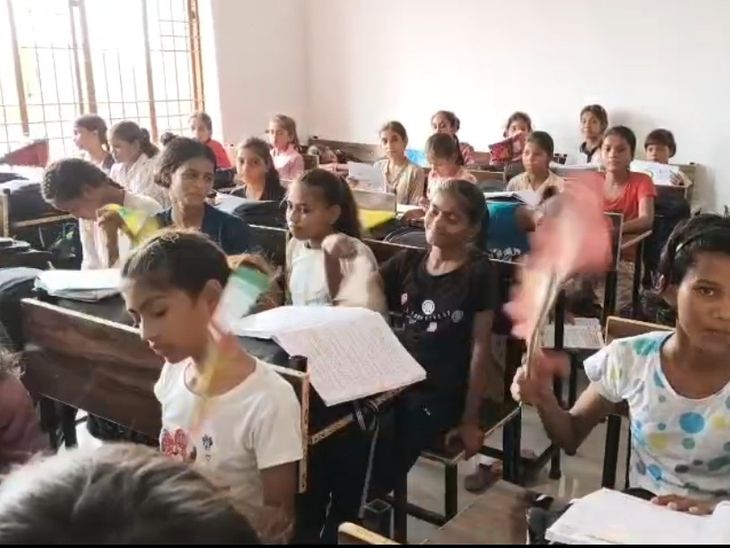 There is no electric fan in the school, children are fanning themselves ...