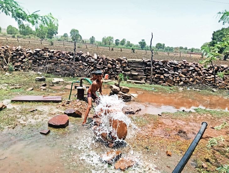 Children bathe at tube wells to escape the scorching heat.