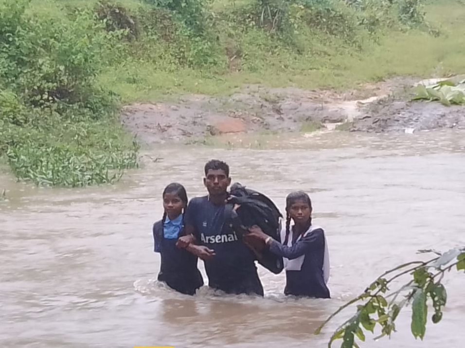 Students passing through a overflowing drain amid rain in Balaghat ...