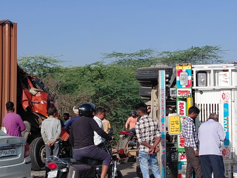 A truck loaded with corn overturned after colliding with a container